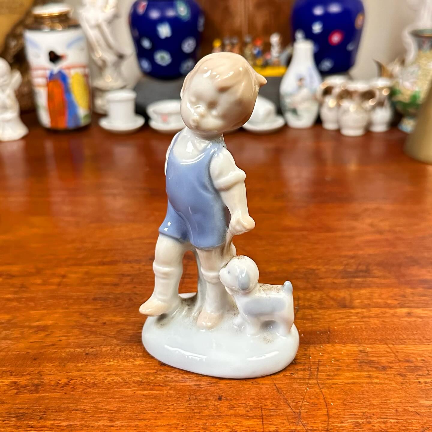 Bibelo em porcelana estilo Lladró menino e cachorro. - Dônama Antiquário